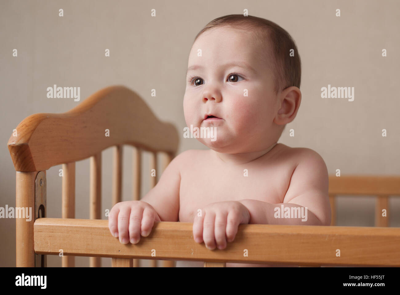 Serious chubby young baby with a focused look standing shirtless in a ...