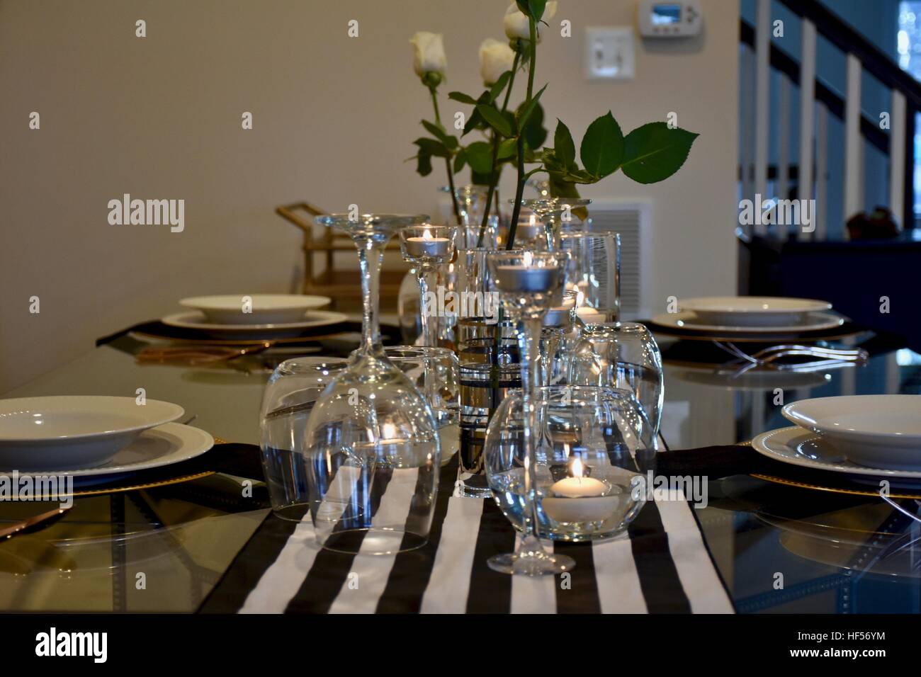 An elegant dinner set up prepared on a beautiful glass table for a ...