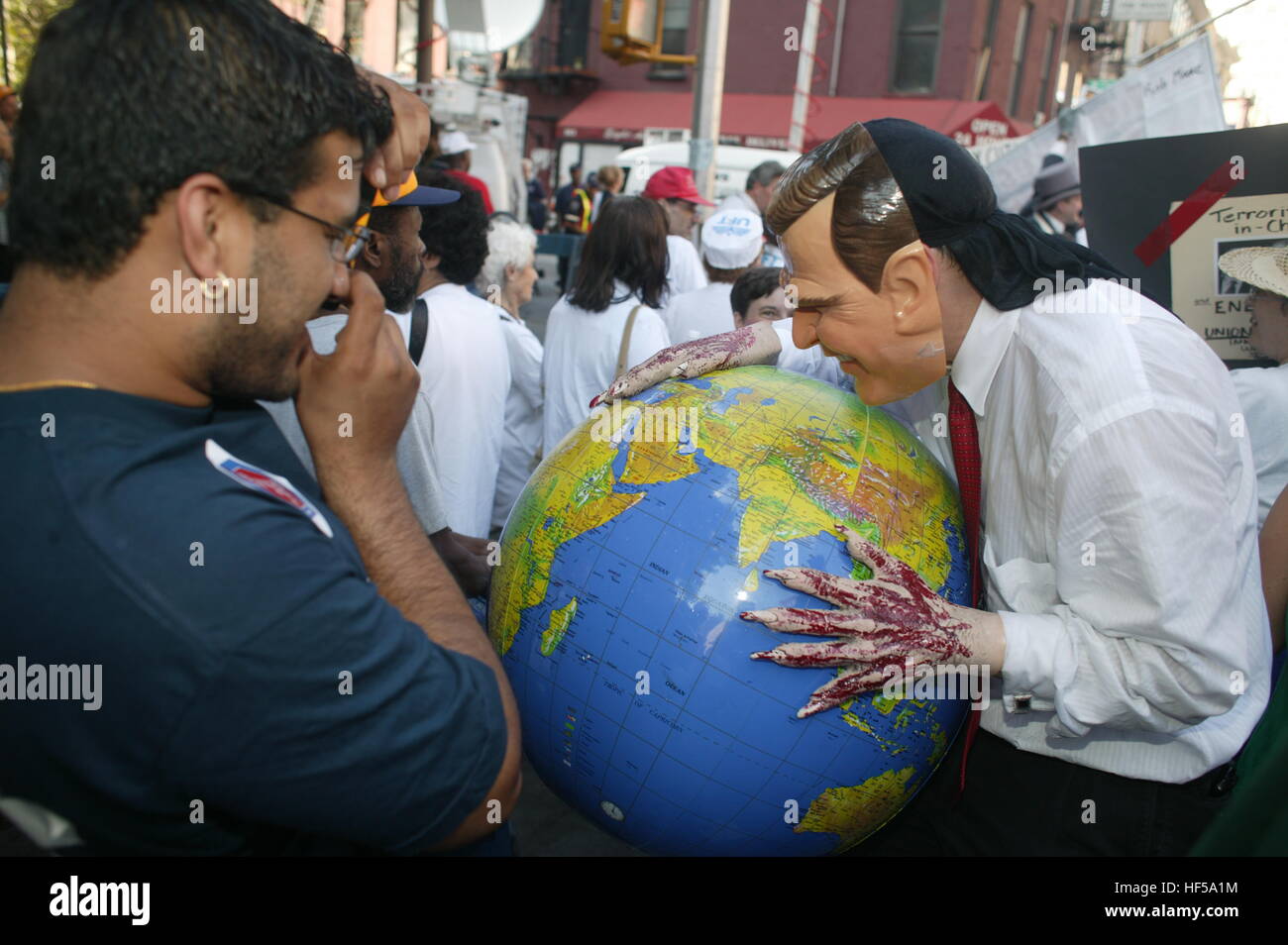 A protester dressed as George W. Bush holds a blow up globe of planet ...