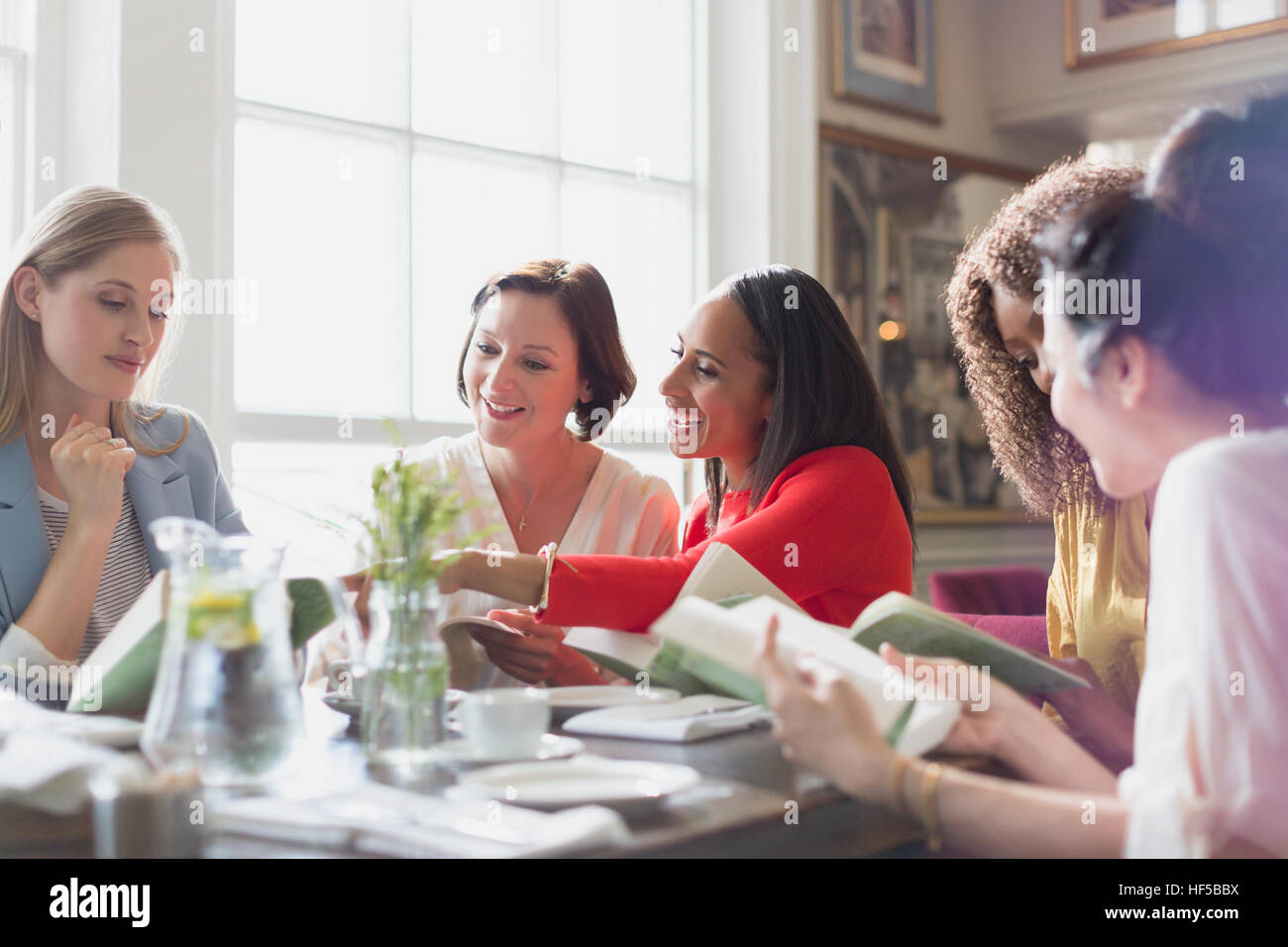 Women friends discussing book club book at restaurant table Stock Photo ...