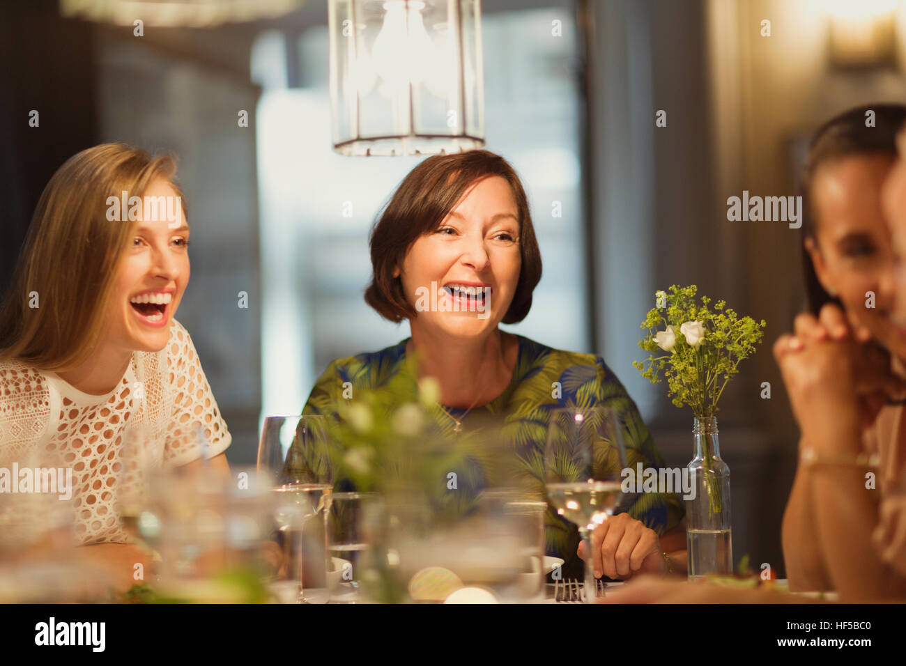 Laughing women friends dining and talking at restaurant table Stock ...
