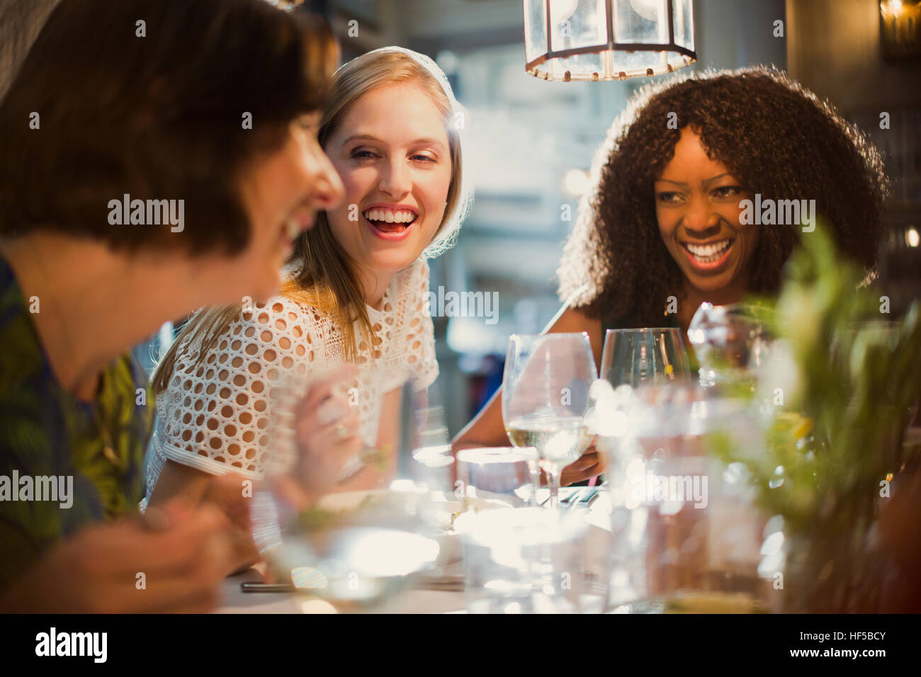 Laughing women friends talking and dining at restaurant table Stock ...