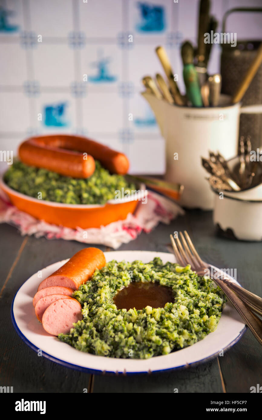A rustic kitchen with a plate with 'Boerenkool met worst' or kale with ...