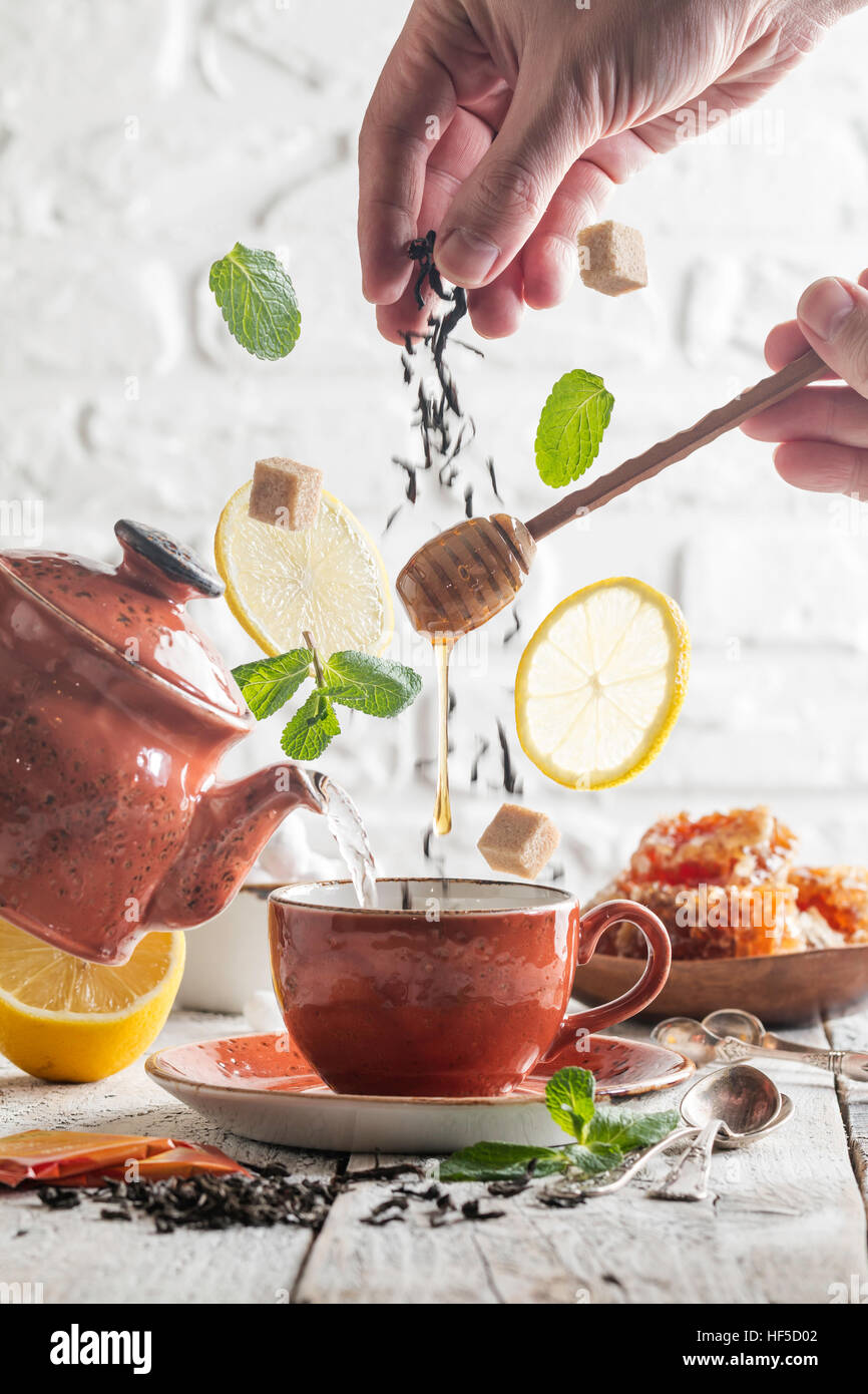 Tea ingredients falling down to the cup on white background. Levitating ...