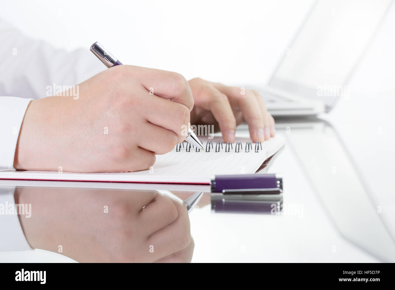 Businessman write a short note on opened notebook with pen and glasses ...