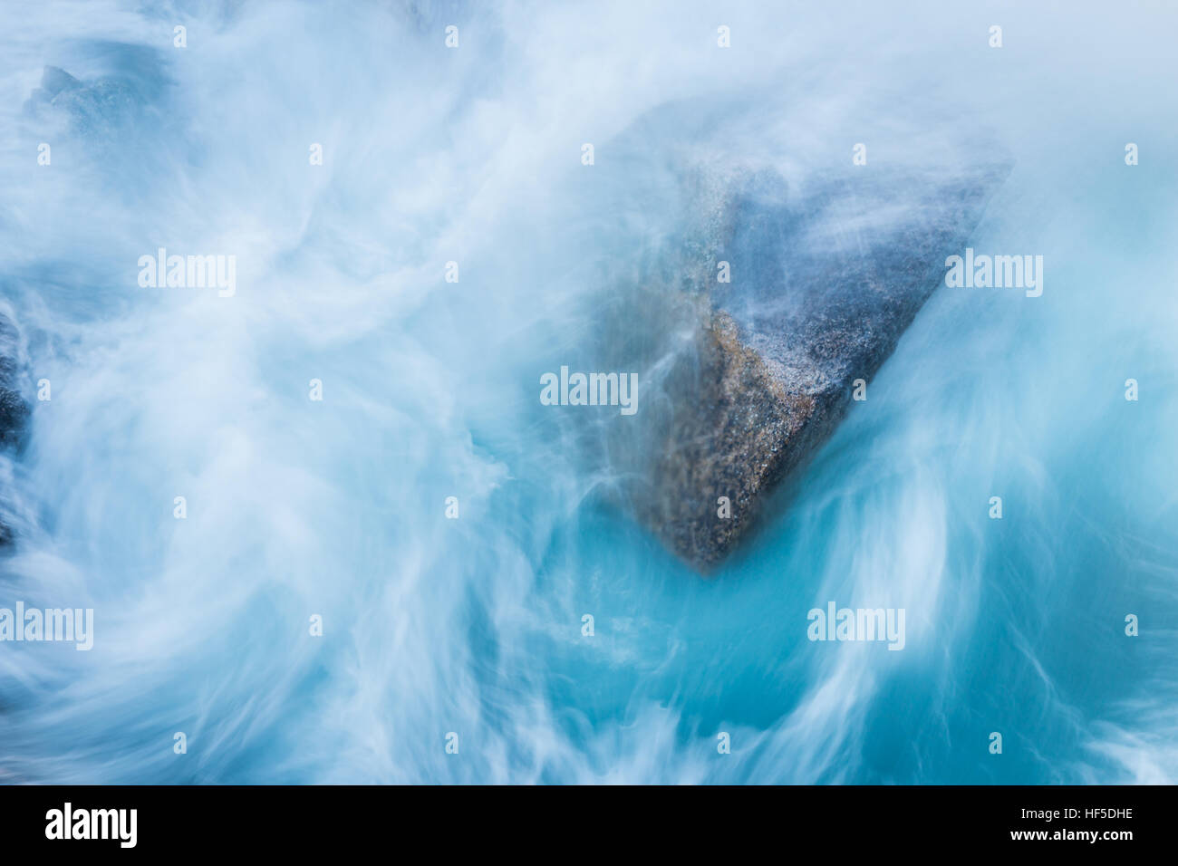 Blue water washes over a rock in a long exposure Stock Photo - Alamy