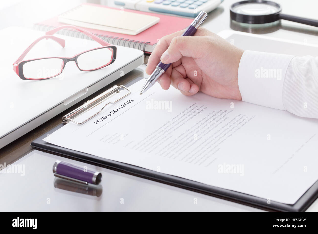 Businessman signing his resignation letter on his desk before sending ...