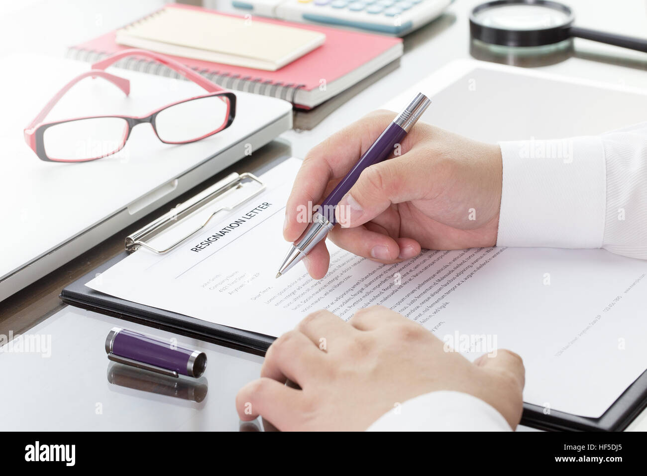 Businessman signing his resignation letter on his desk before sending ...