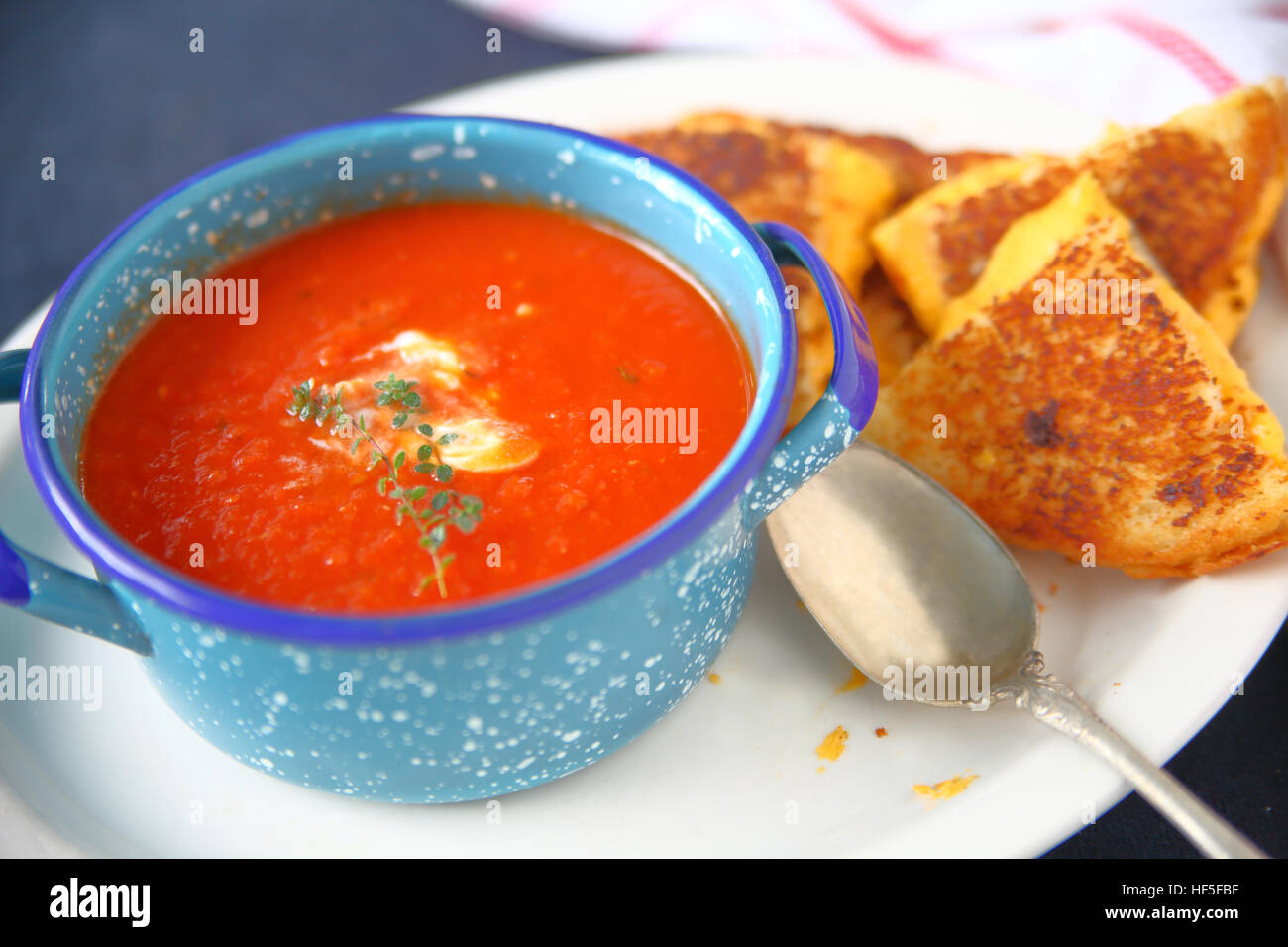 Blue bowl of tomato soup with fresh thyme and a grilled cheese sandwich ...
