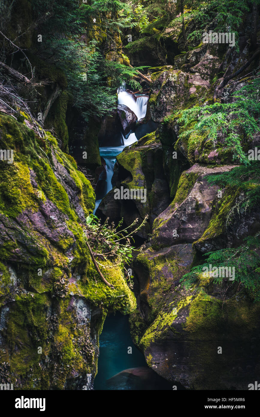 Waterfall flowing past moss covered boulders Stock Photo - Alamy