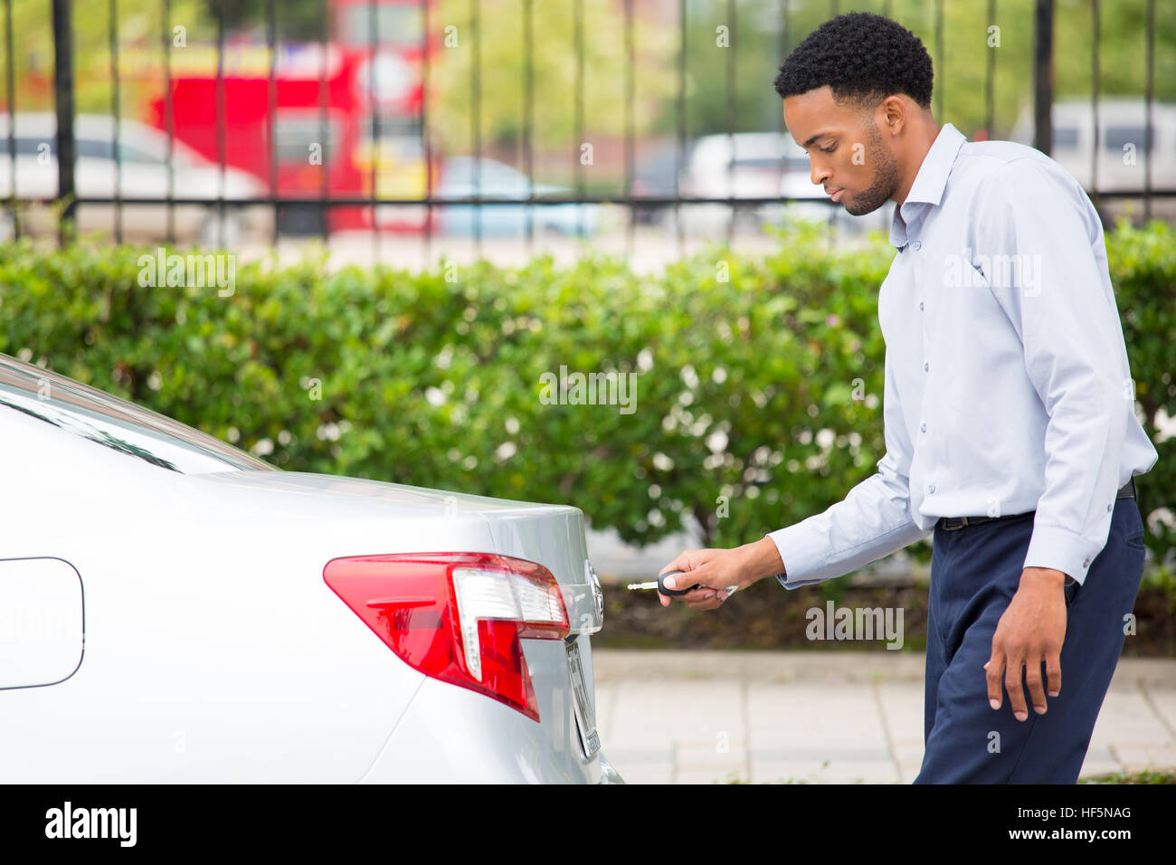 Closeup portrait of a young man trying to open the trunk of his brand ...