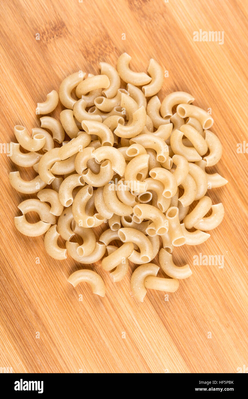 Brown rice elbow macaroni isolated on a wood background Stock Photo - Alamy