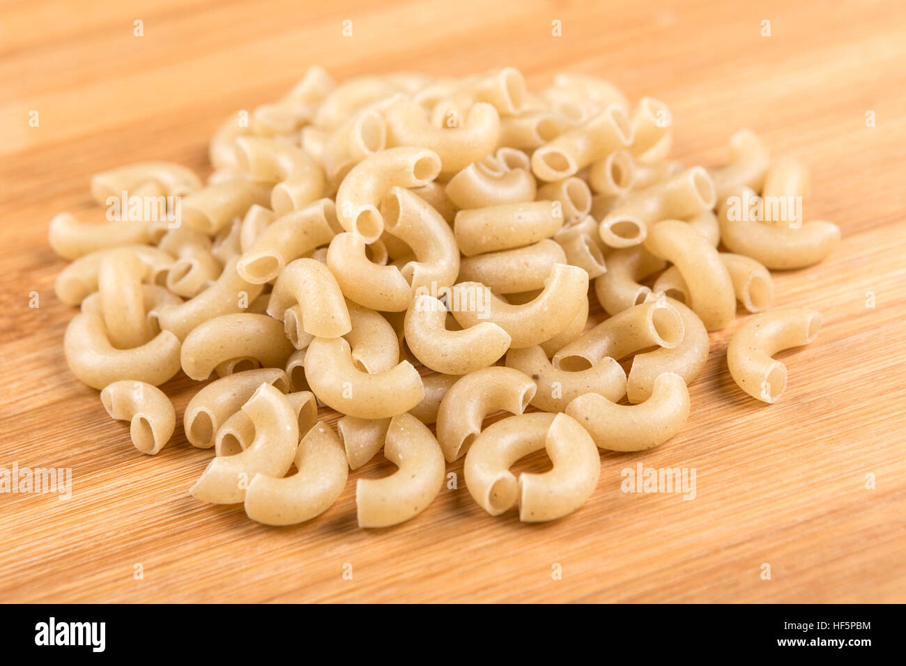 Brown rice elbow macaroni isolated on a wood background Stock Photo - Alamy