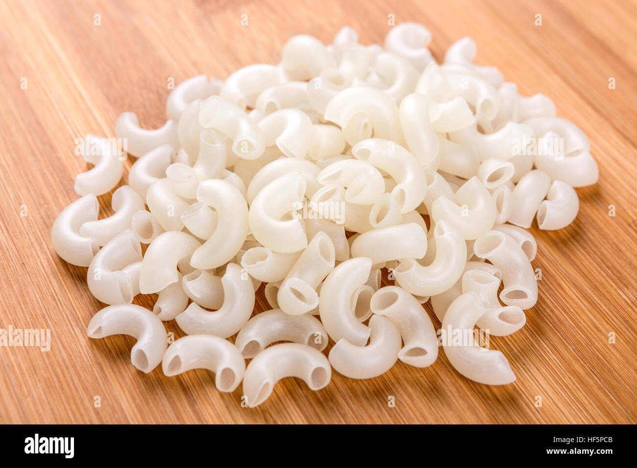 White rice elbow macaroni isolated on a wood background Stock Photo - Alamy