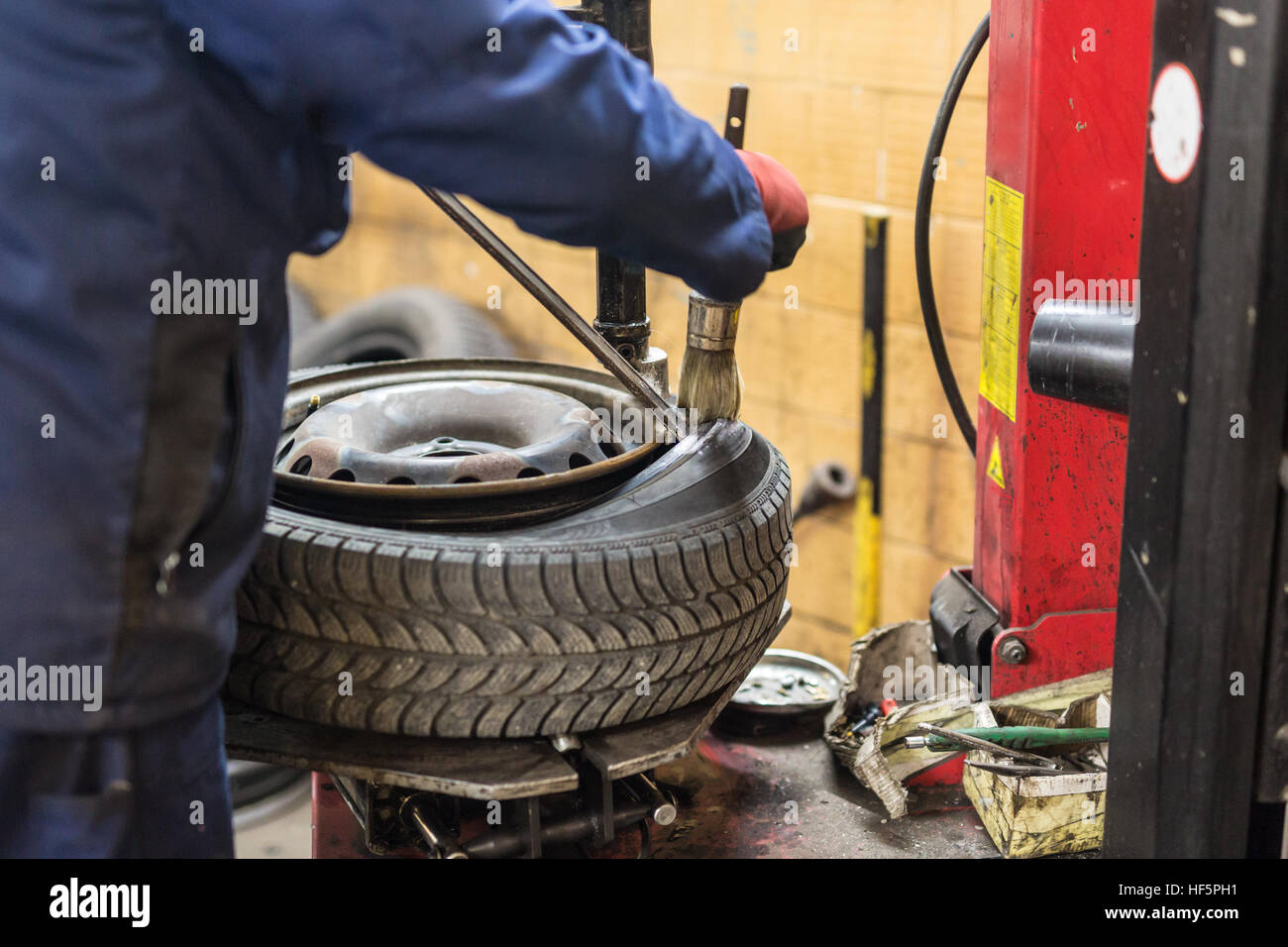 Professional auto mechanic replacing tire on wheel in car repair ...