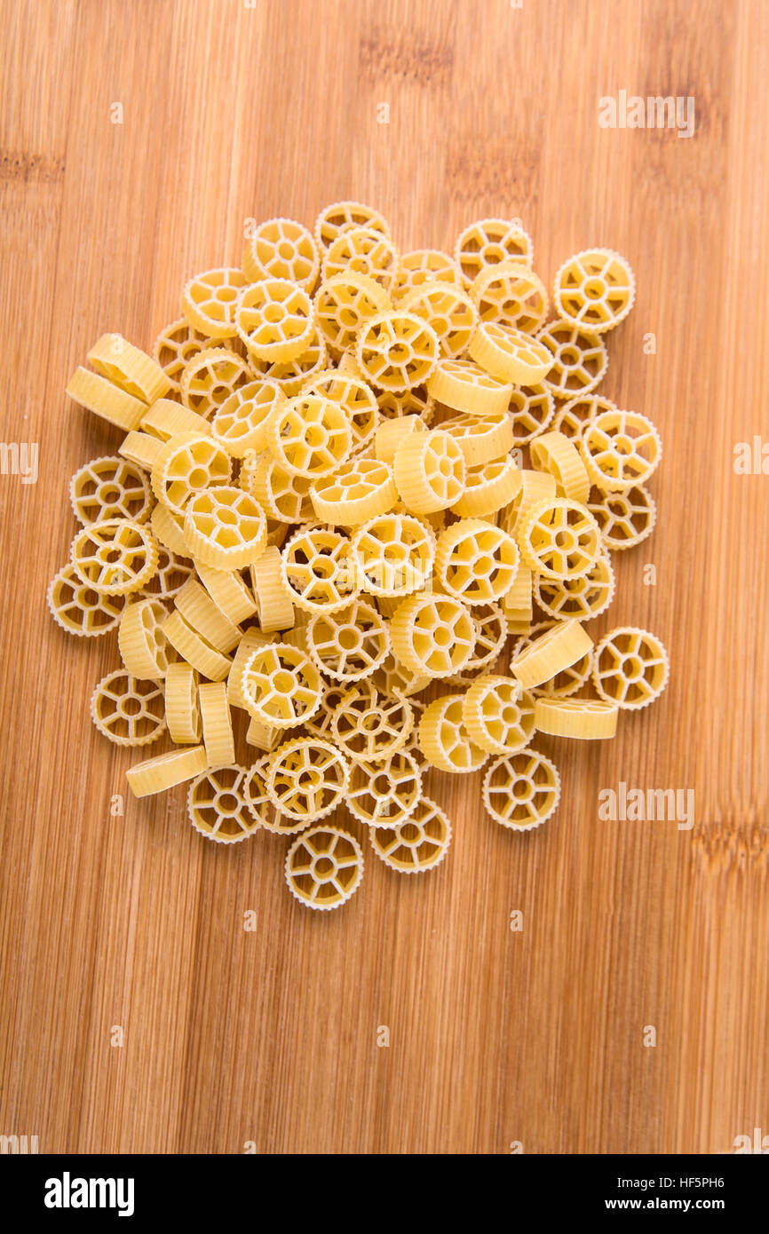 Wheat wagon wheel pasta isolated on a wood background Stock Photo - Alamy