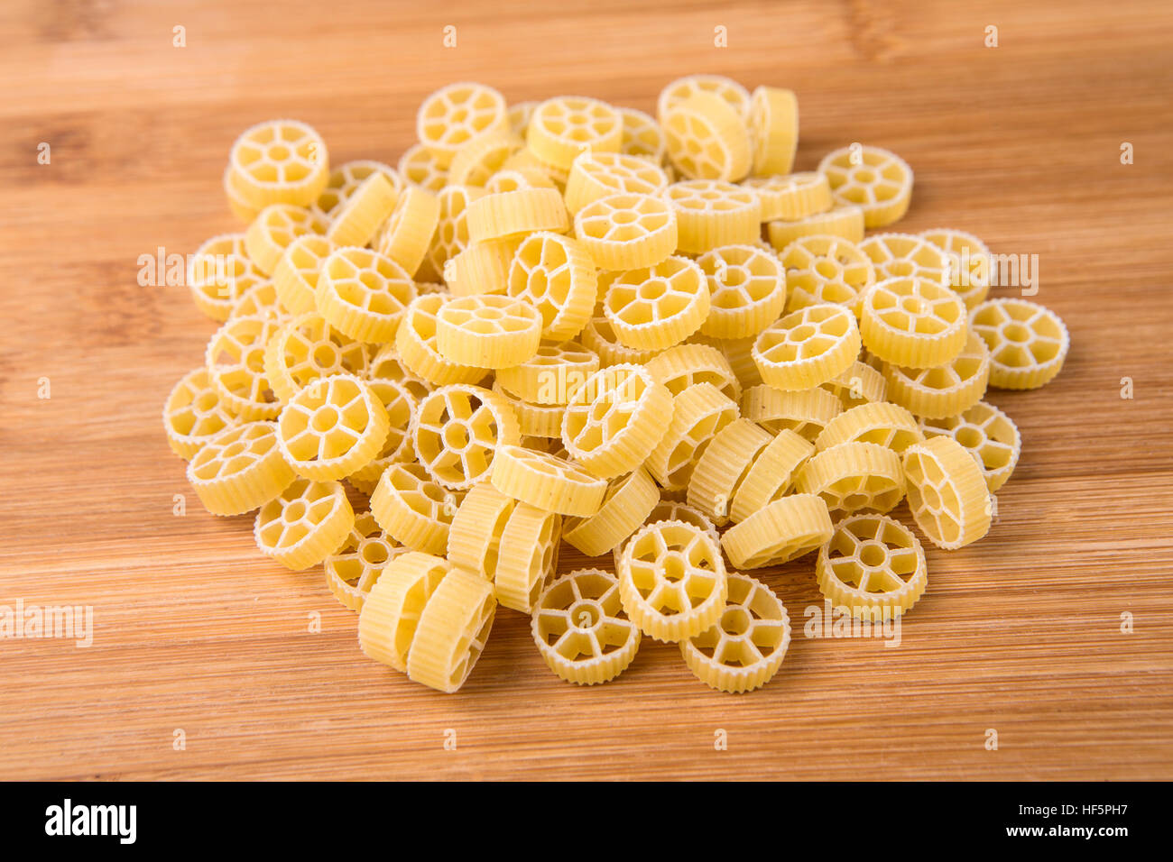 Wheat wagon wheel pasta isolated on a wood background Stock Photo - Alamy
