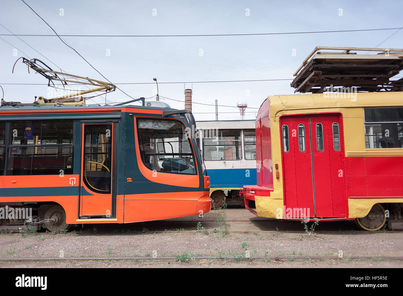 Trams new and old, are in a park, ready to travel the route. past ...