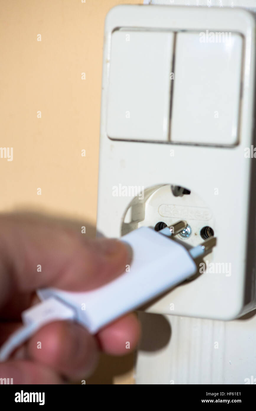 hand with plug at electricity point Stock Photo - Alamy