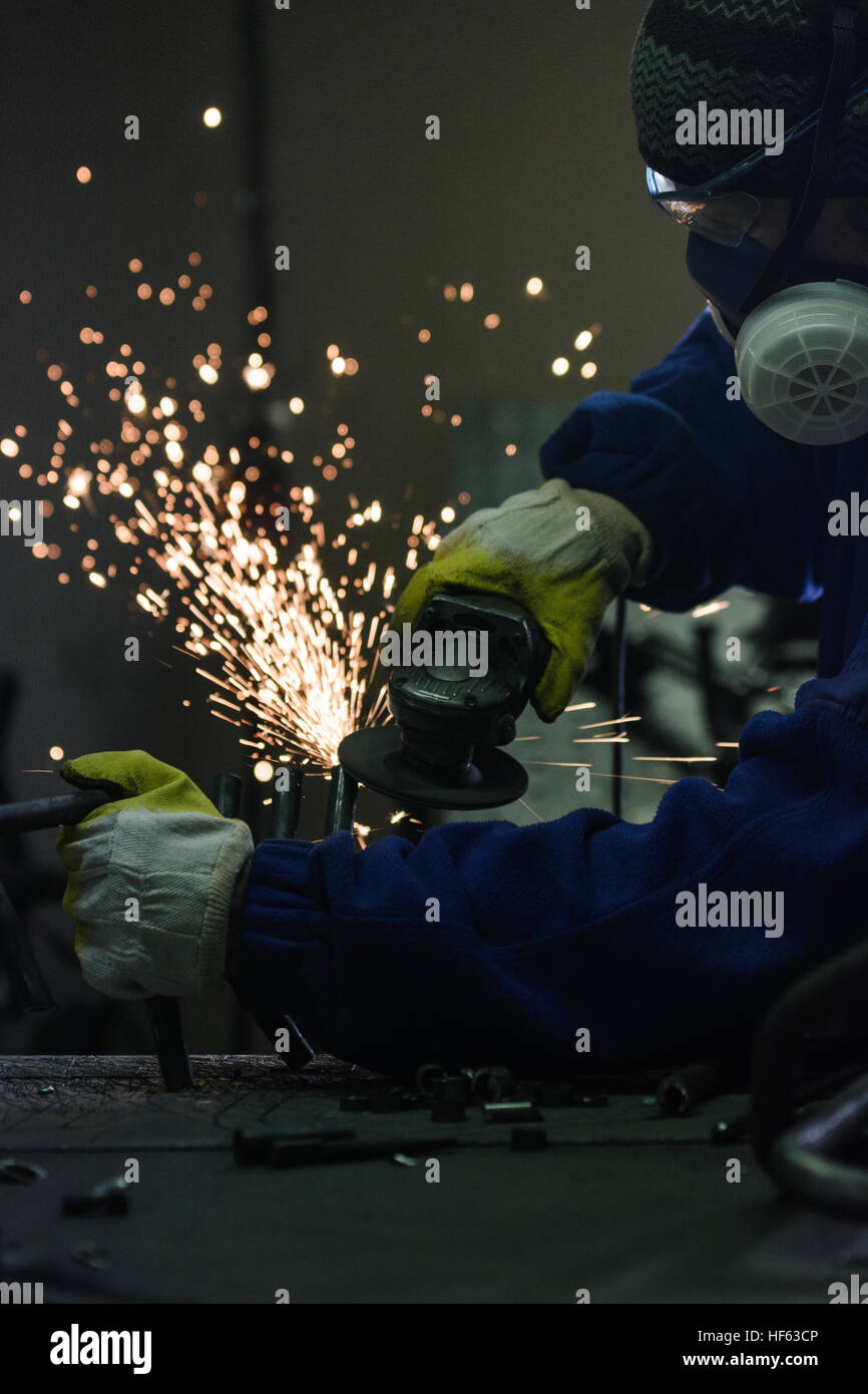 Man sawing metal with a rotary angle grinder on an aluminium surface ...