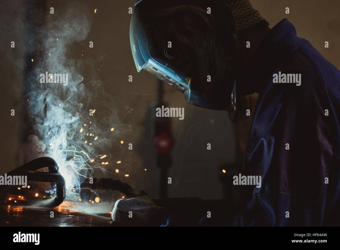 Worker with protective mask welding metal and producing smoke and ...