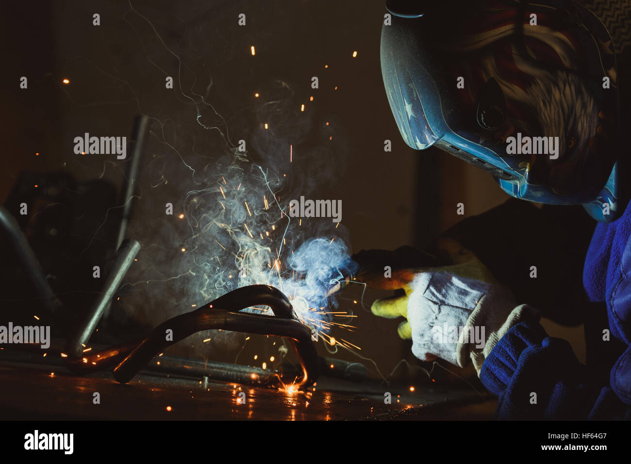 Worker with protective mask welding metal and producing smoke and ...