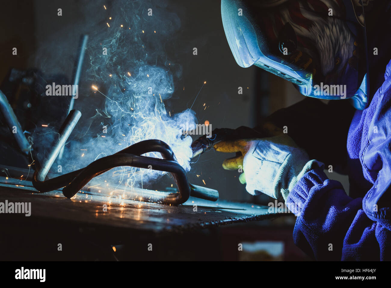 Worker with protective mask welding metal and producing smoke and ...