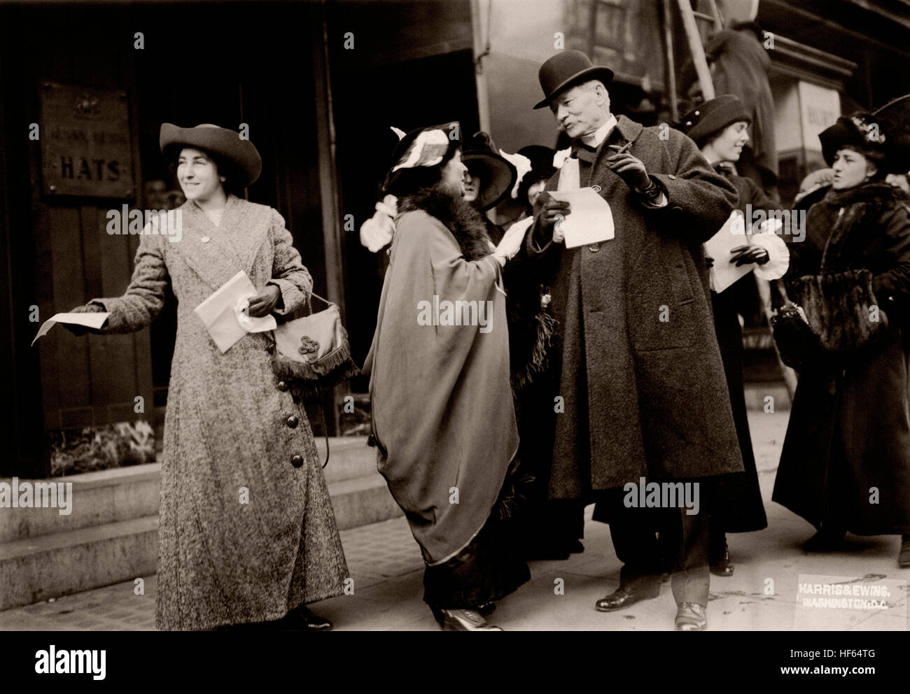 Suffragists on a city sidewalk handing out suffrage handbills to people ...