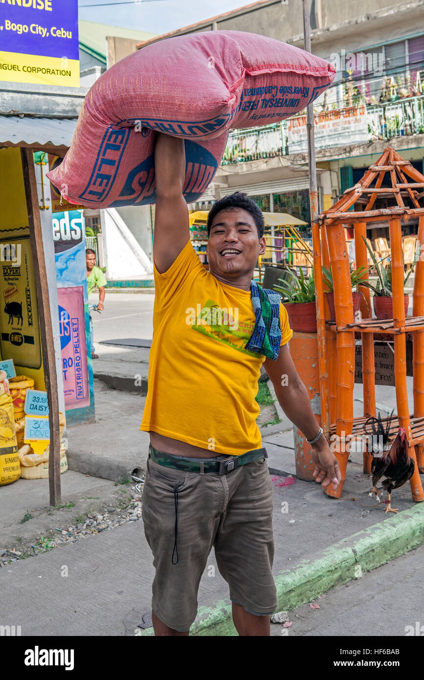 A Filipino teenage boy holds a 50-pound sack of white rice over his ...