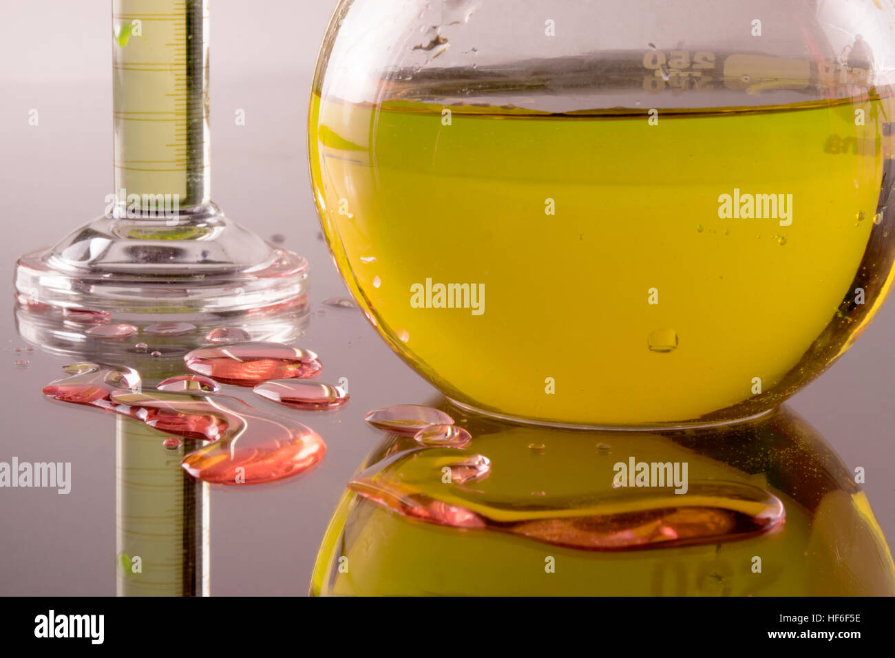spilled yellow chemistry and graduated cylinder Stock Photo - Alamy