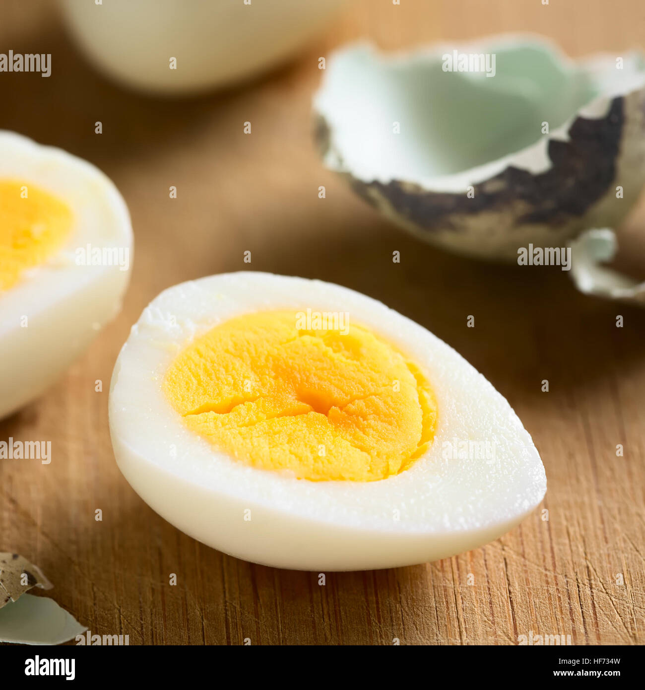 Hard boiled quail egg half with egg shells on wooden board ...