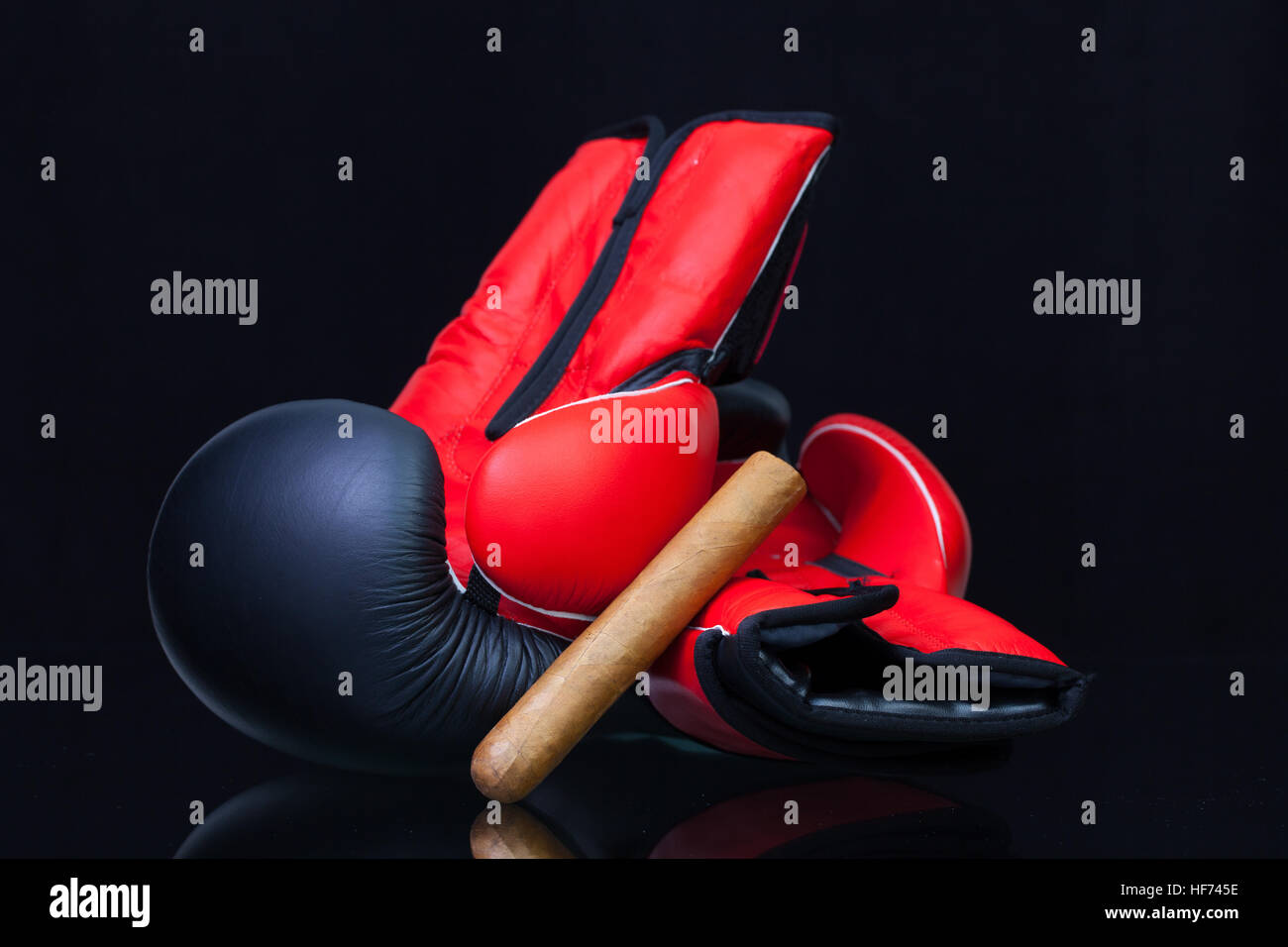 Red and black boxing gloves and luxury Cuban cigar on black glass table ...