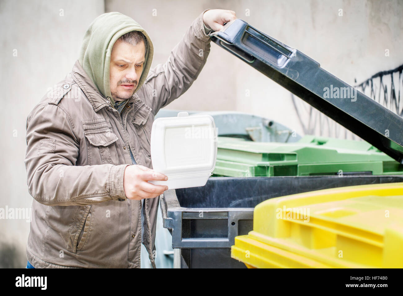 Homeless near garbage container with opened food box Stock Photo - Alamy