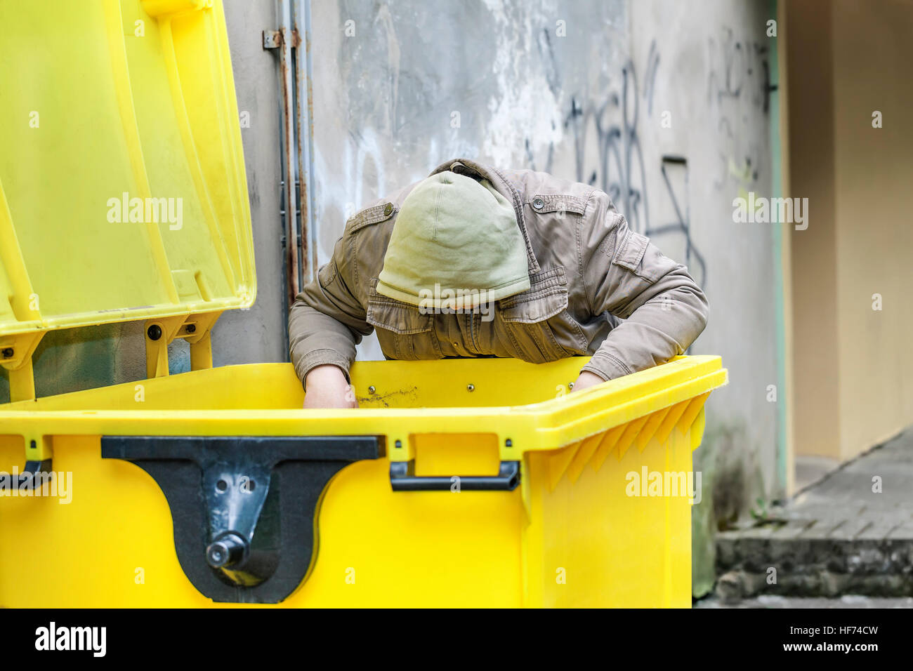 Homeless near yellow garbage container Stock Photo - Alamy