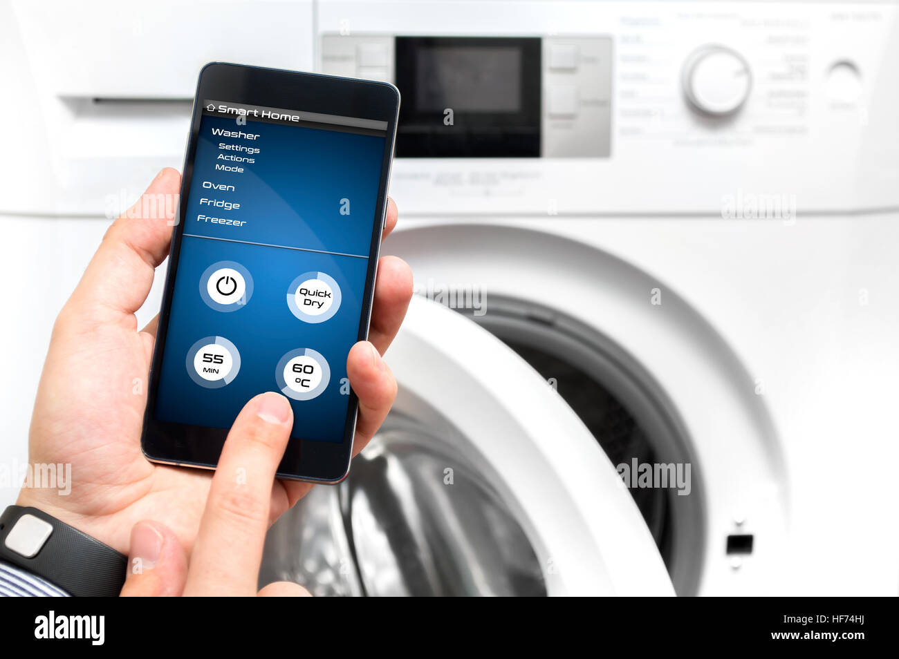 Man uses his smartphone to set up the washer Stock Photo - Alamy