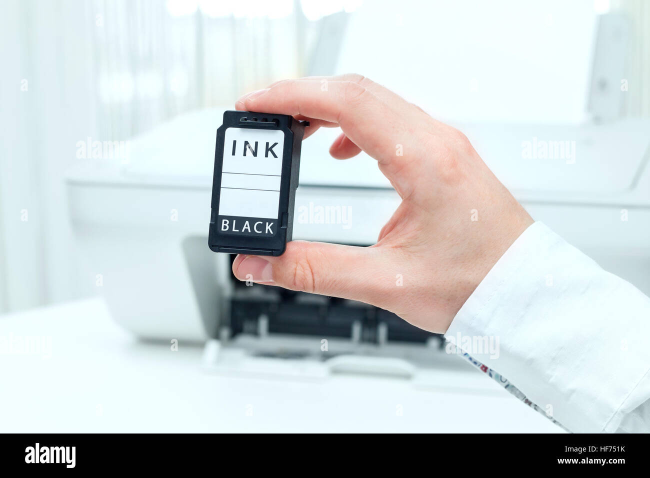 Man shows black ink cartridge from white printer Stock Photo - Alamy