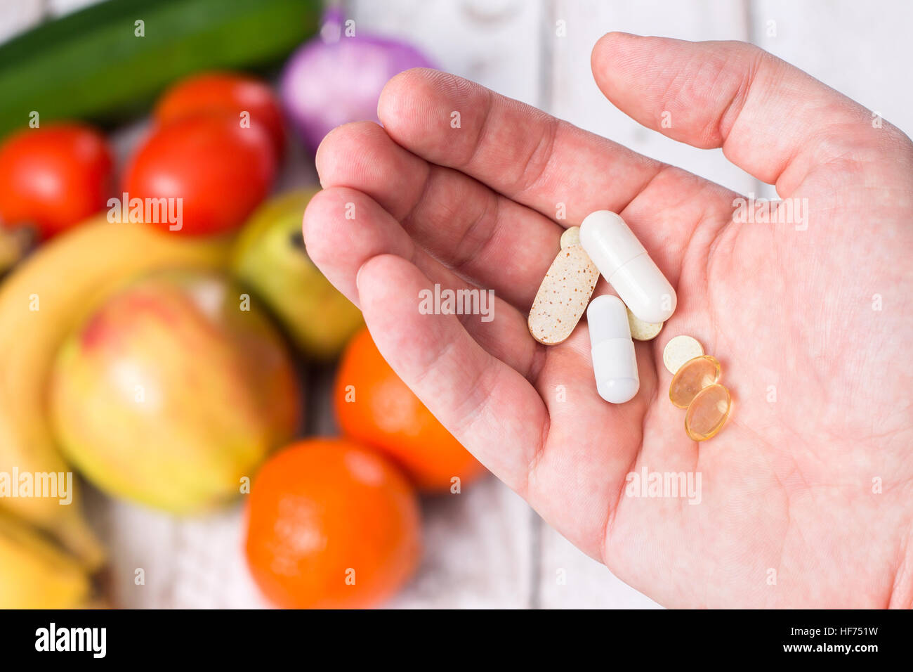 Hand with dietary supplements on fruity background Stock Photo - Alamy