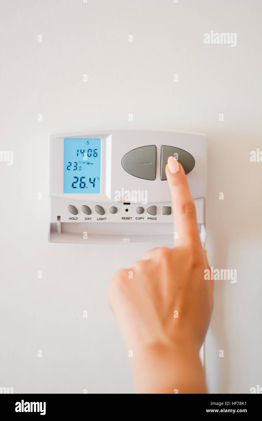 Adjust temperature with thermostat in home interior Stock Photo - Alamy