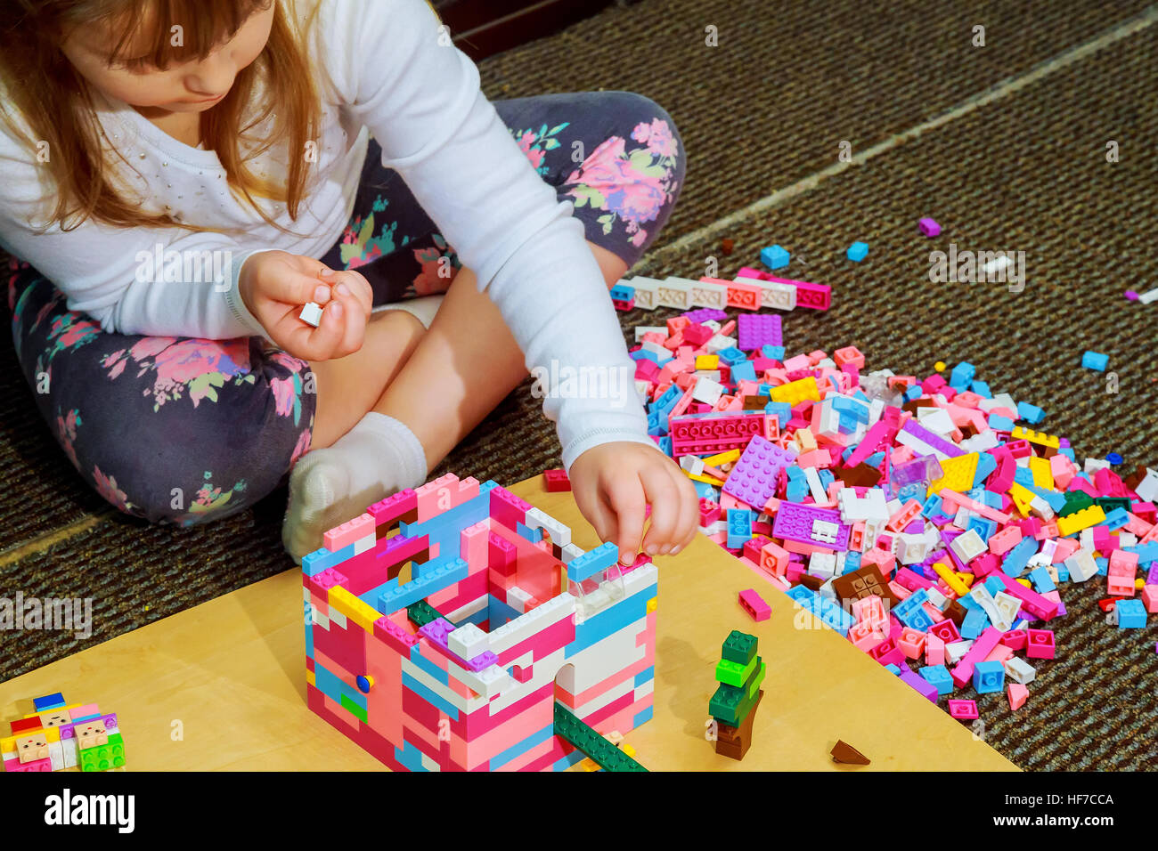 Child girl having fun and build of bright plastic construction blocks ...