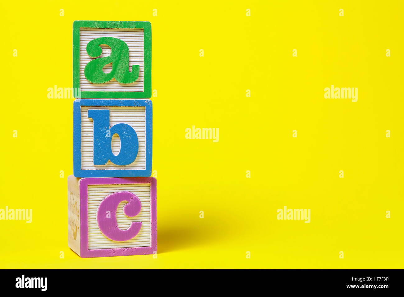ABC Alphabet blocks stacked up on yellow background Stock Photo - Alamy