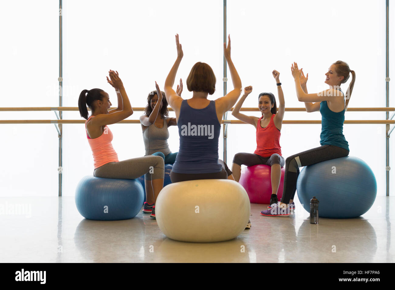 Women on fitness balls cheering and clapping in gym studio Stock Photo ...