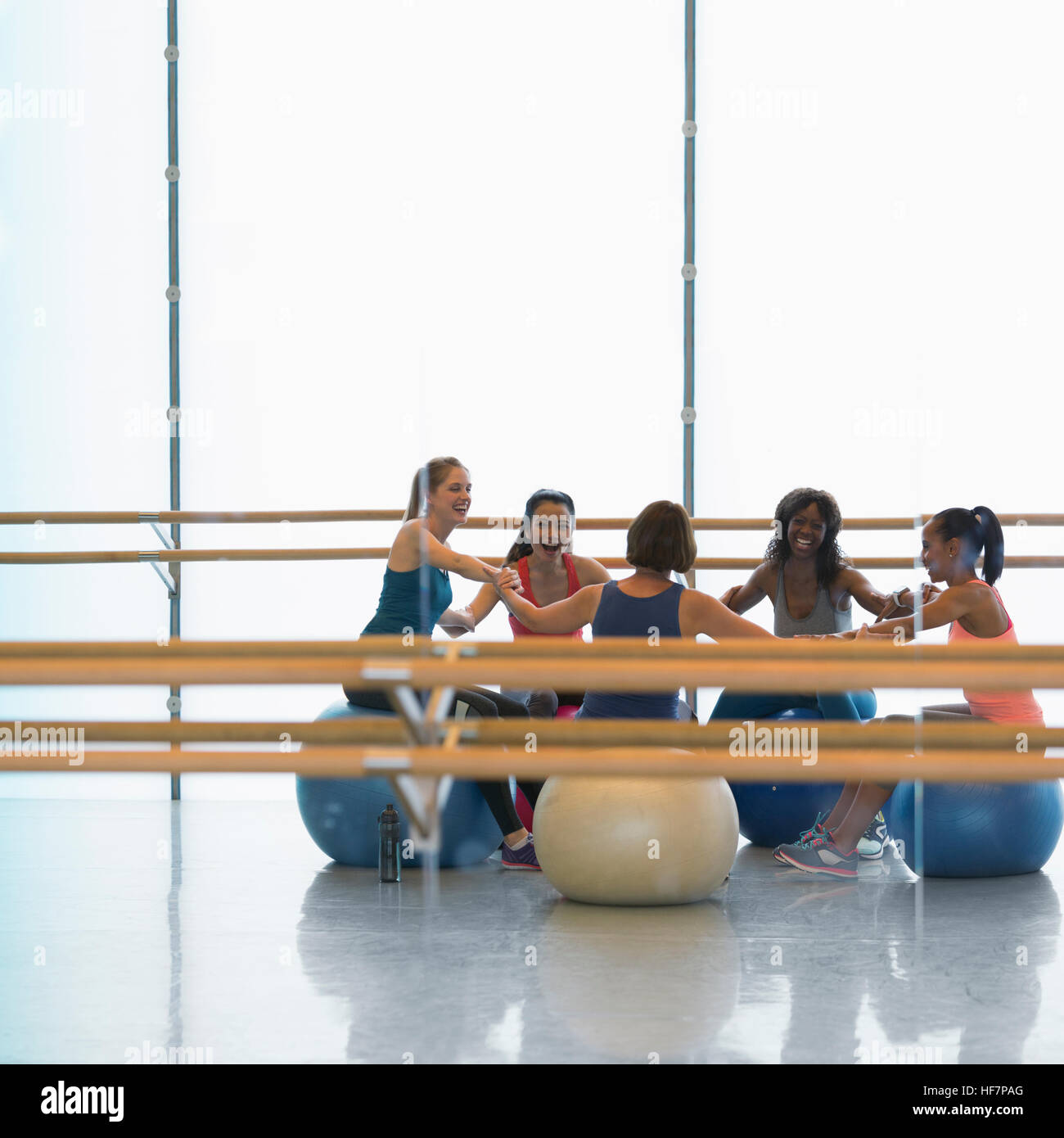 Smiling women holding hands on fitness balls in gym studio Stock Photo ...