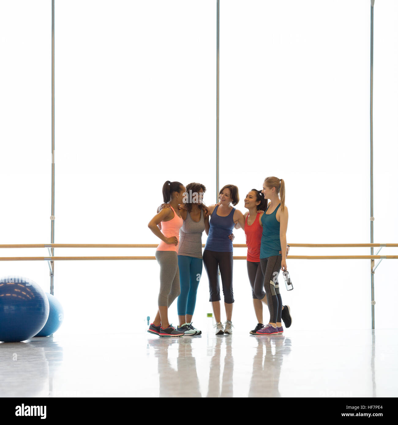 Smiling women friends talking in exercise class gym studio Stock Photo ...