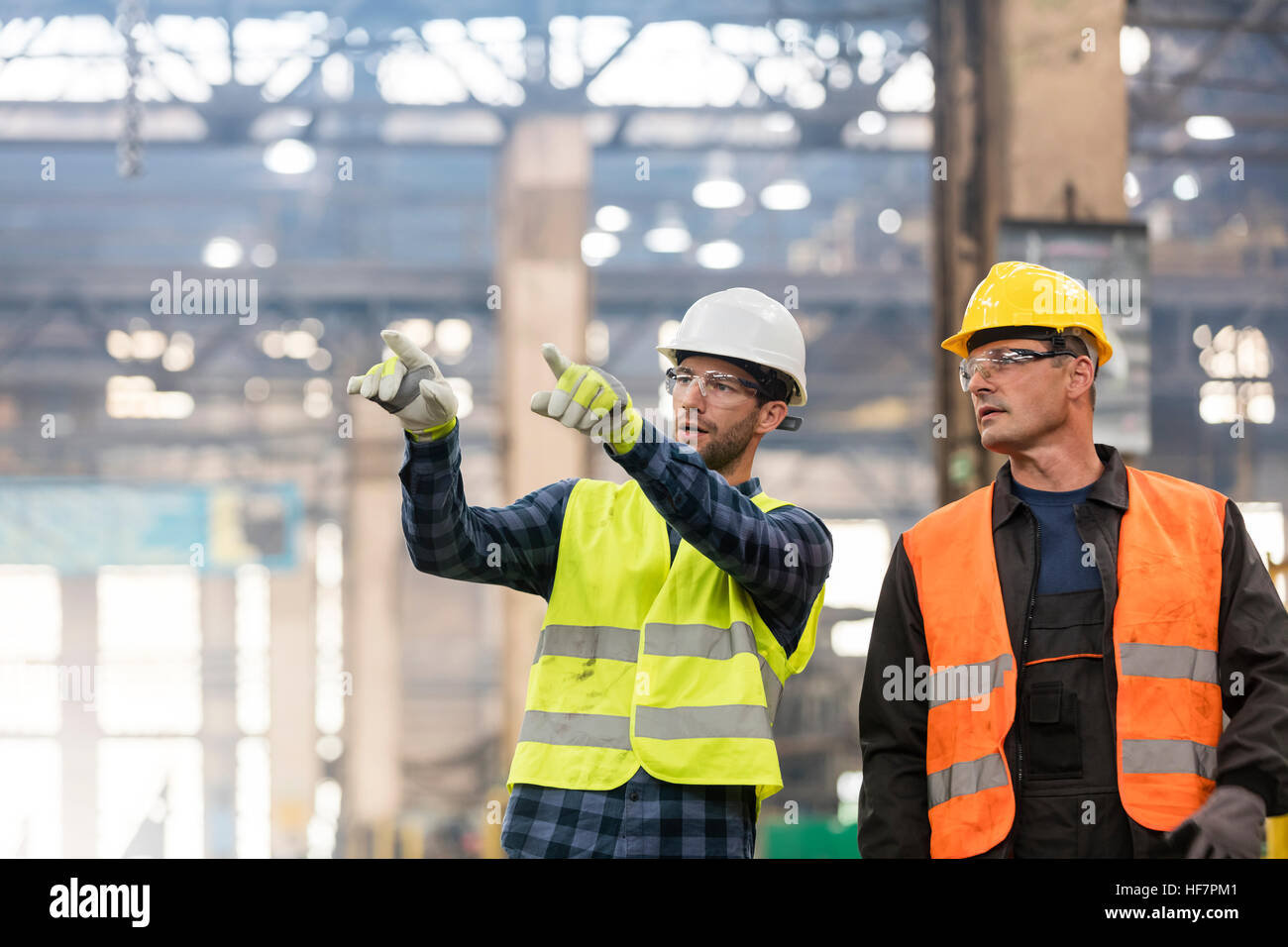 Steel workers talking and pointing in factory Stock Photo - Alamy