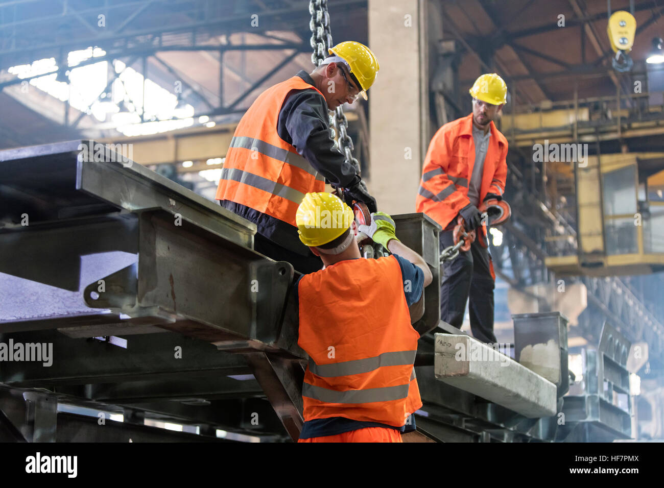 Steel workers fastening crane hook to steel in worker Stock Photo - Alamy