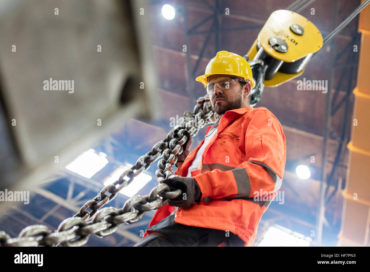 Steel worker holding crane chain in factory Stock Photo - Alamy