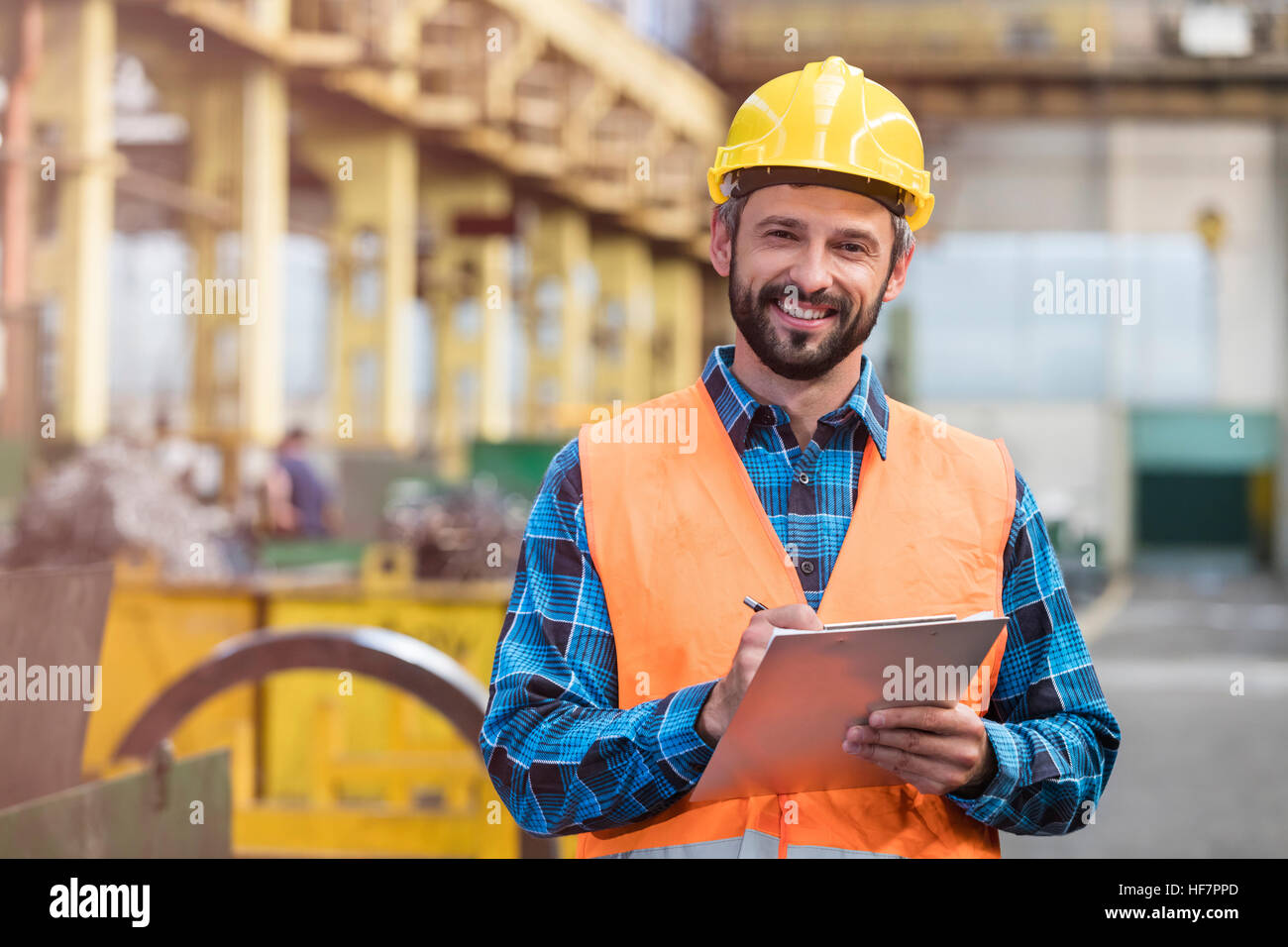 Portrait smiling steel worker with clipboard in factory Stock Photo - Alamy