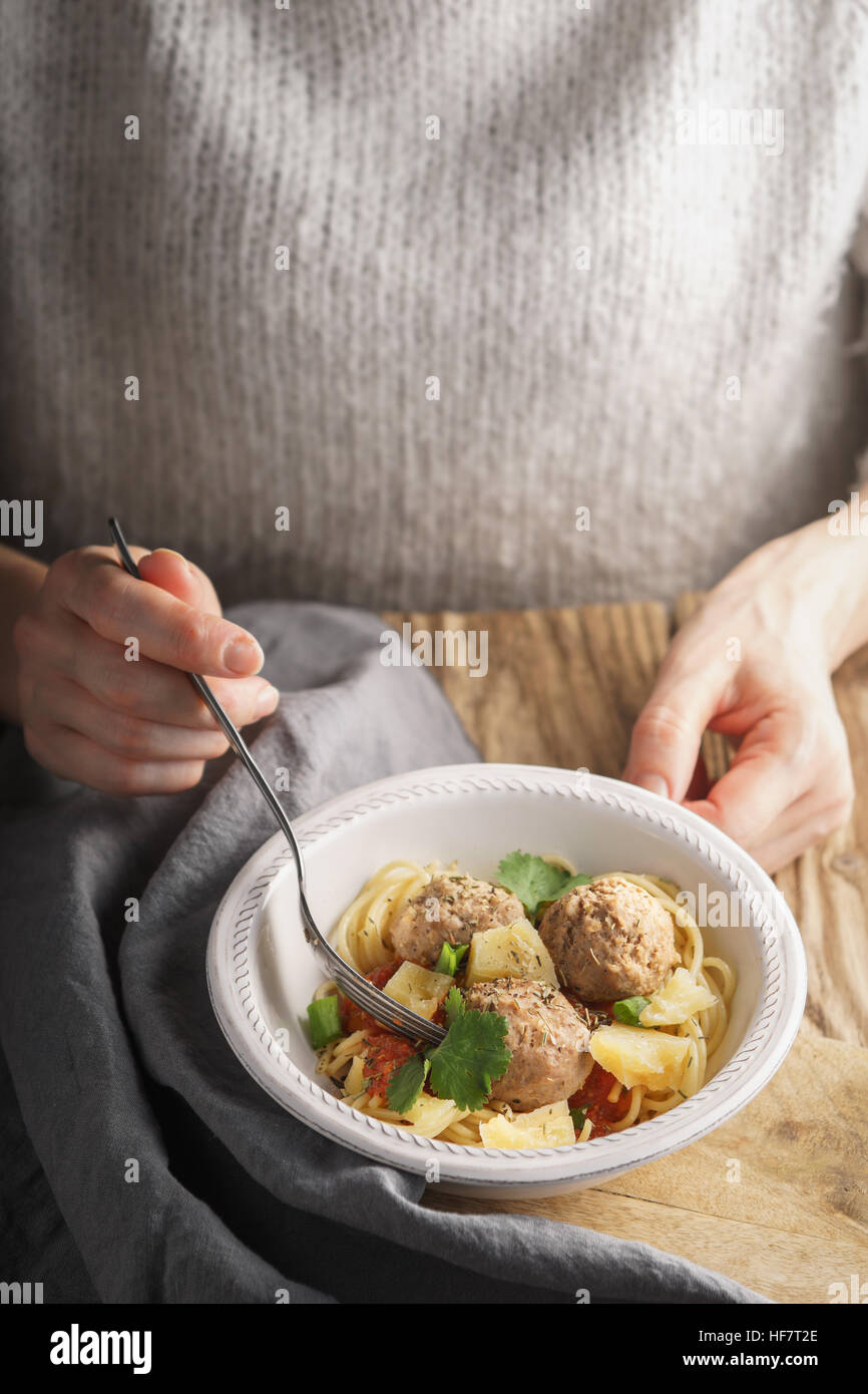 Woman eating spaghetti with meatballs and cheese from a bowl vertical ...