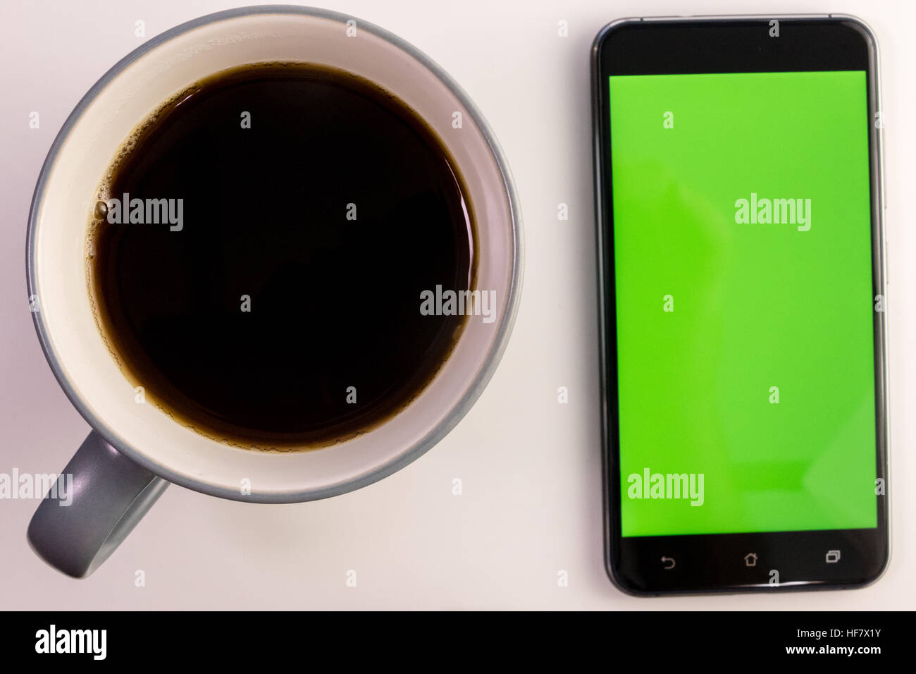 Smart phone with green screen on display next to coffee cup Stock Photo ...