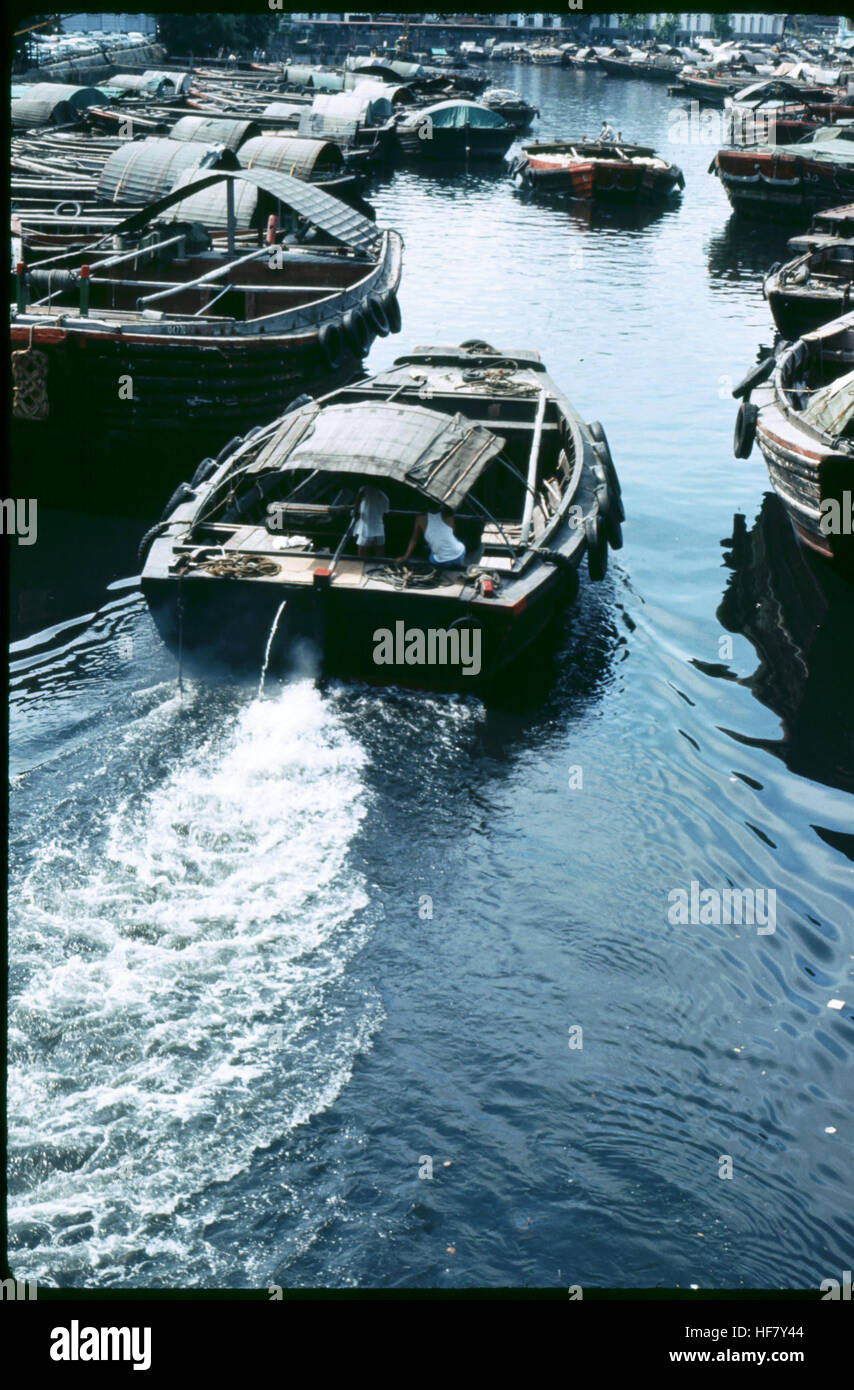 This photograph shows a sampan, a traditional wooden boat, navigating ...